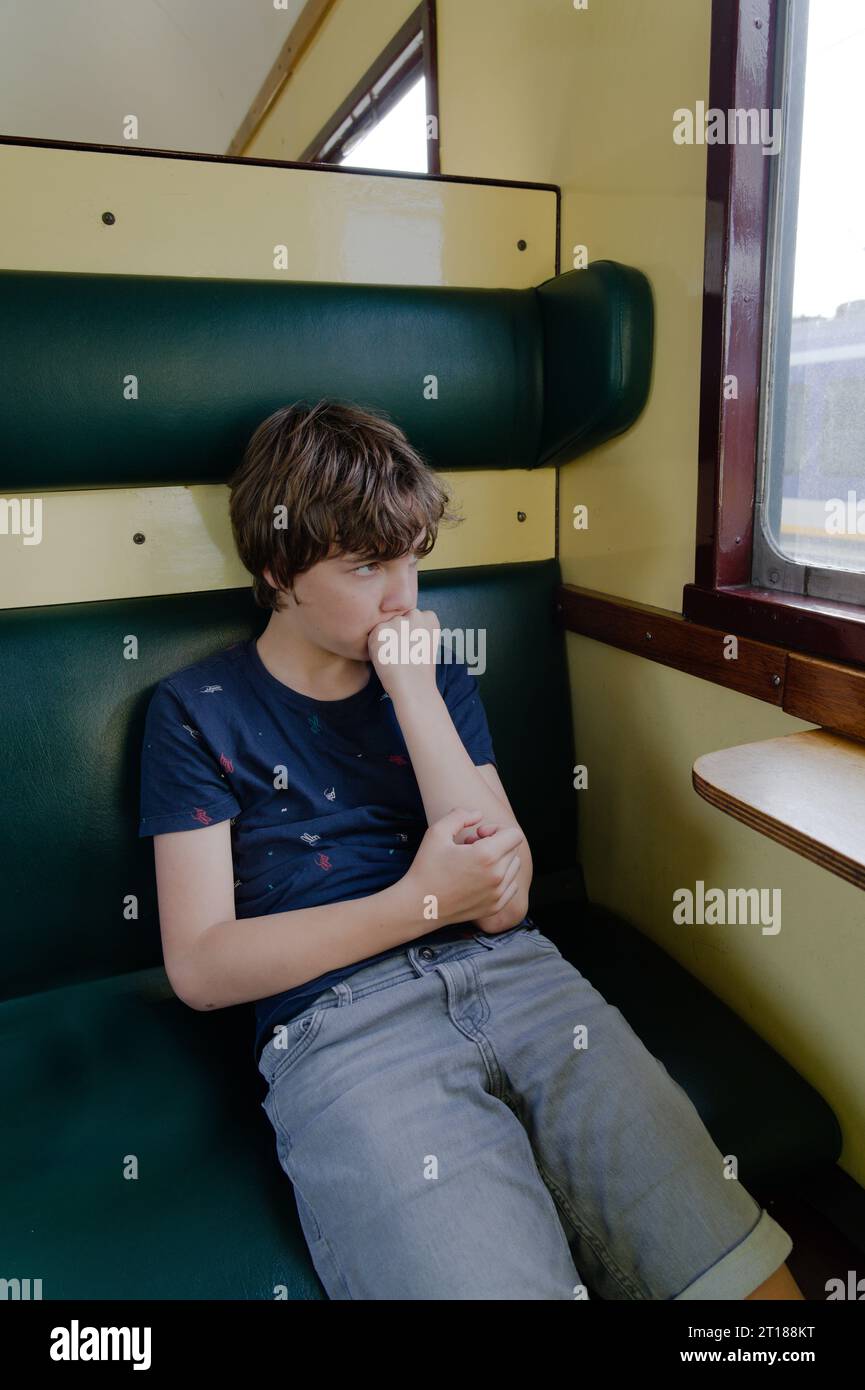 Child sitting alone and looking out the window of the old train car ...