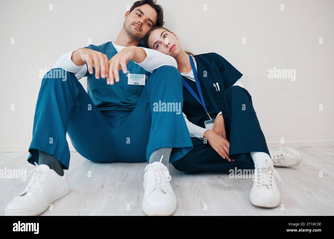 Sad doctors, hospital floor and woman with man, support and lost with regret, death and fail in ...