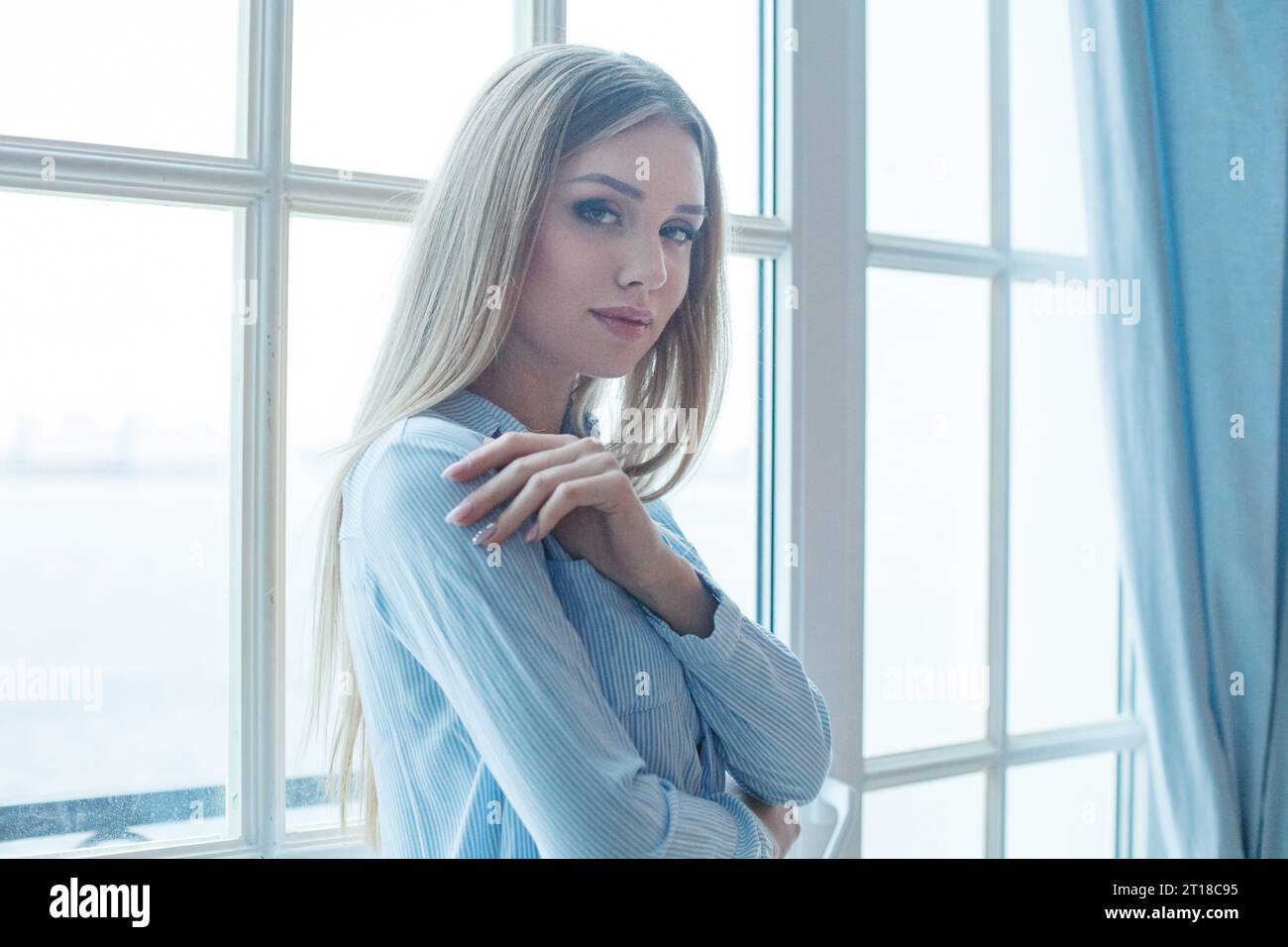 Lovely young woman with long blonde hair and makeup posing in front of ...