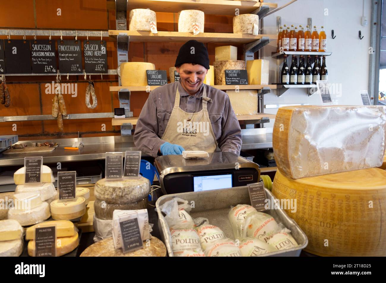 Interior view of Mons Cheesemongers worker weighing cheese on scales in ...