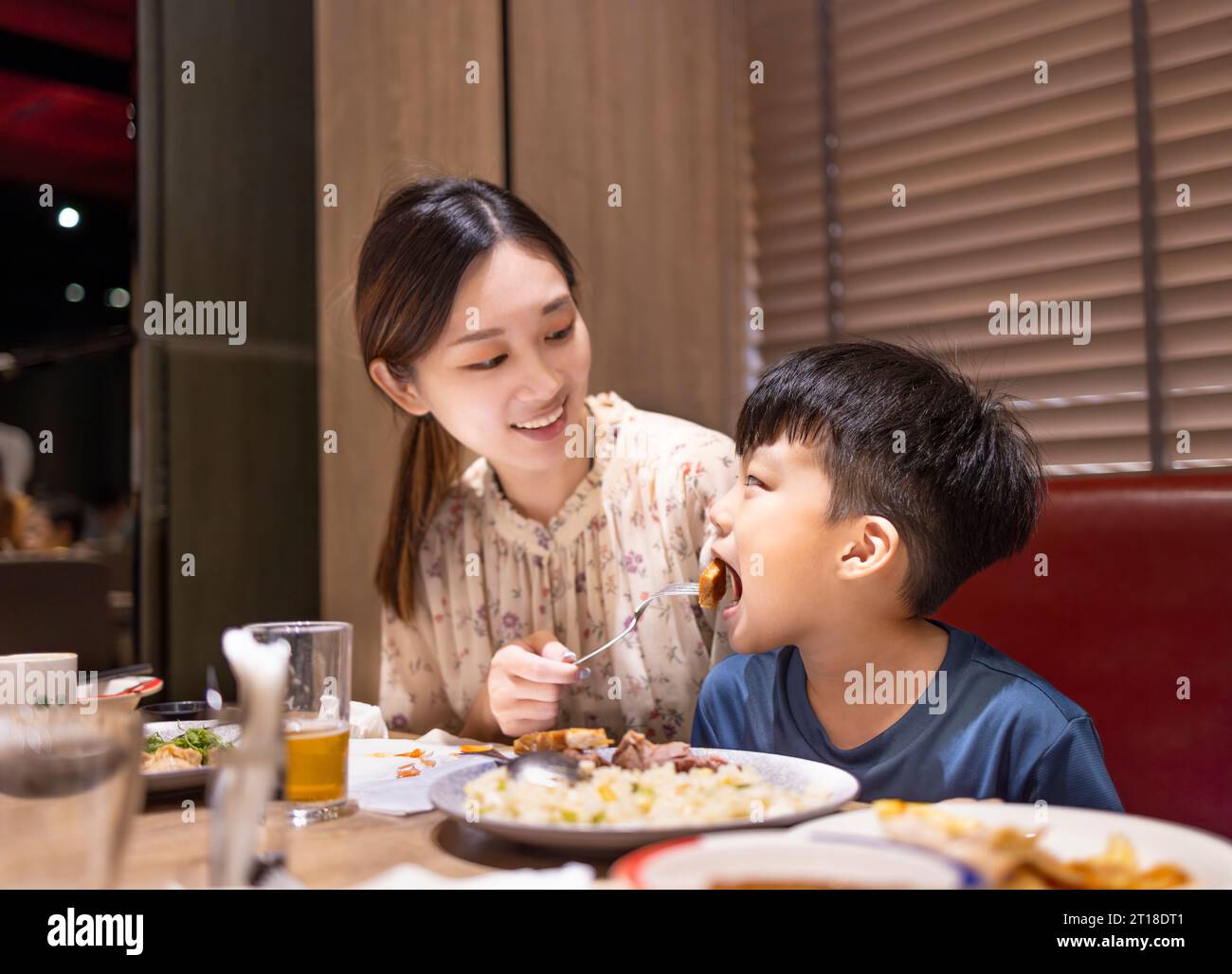 Happy mother feeds her son in restaurant Stock Photo - Alamy