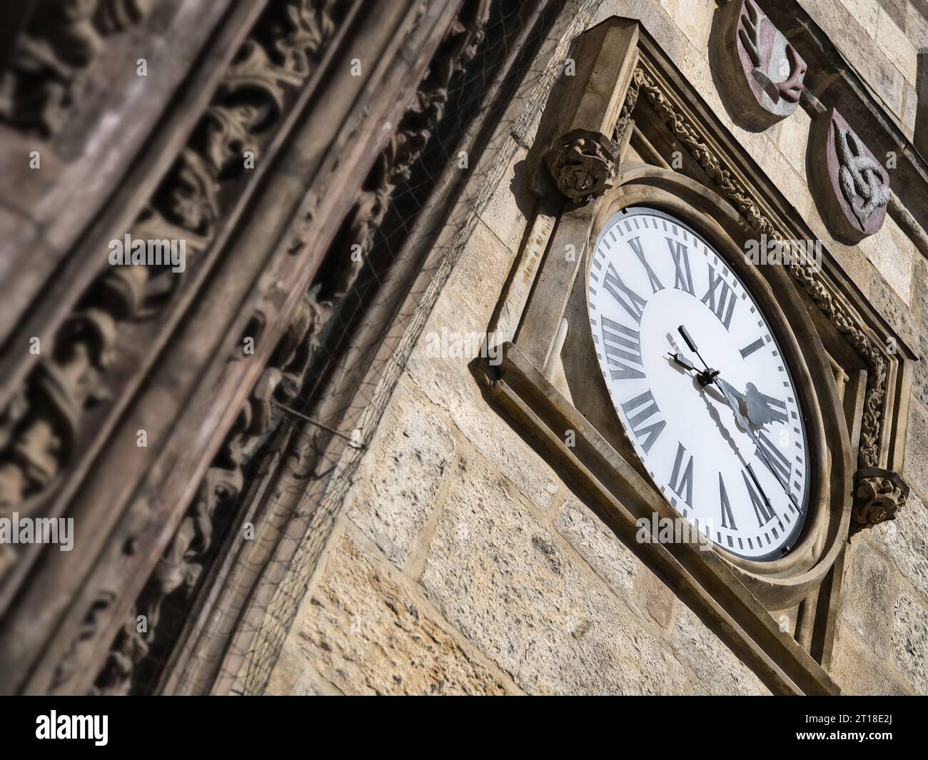 A clock with Roman numerals on the side stone wall of the Prague ...