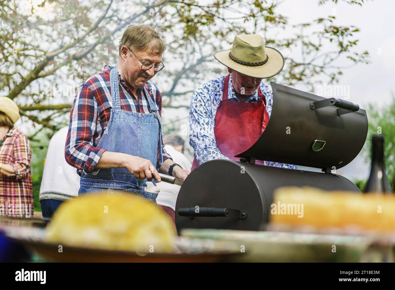 Two cheerful seniors share a playful moment while grilling at a ...