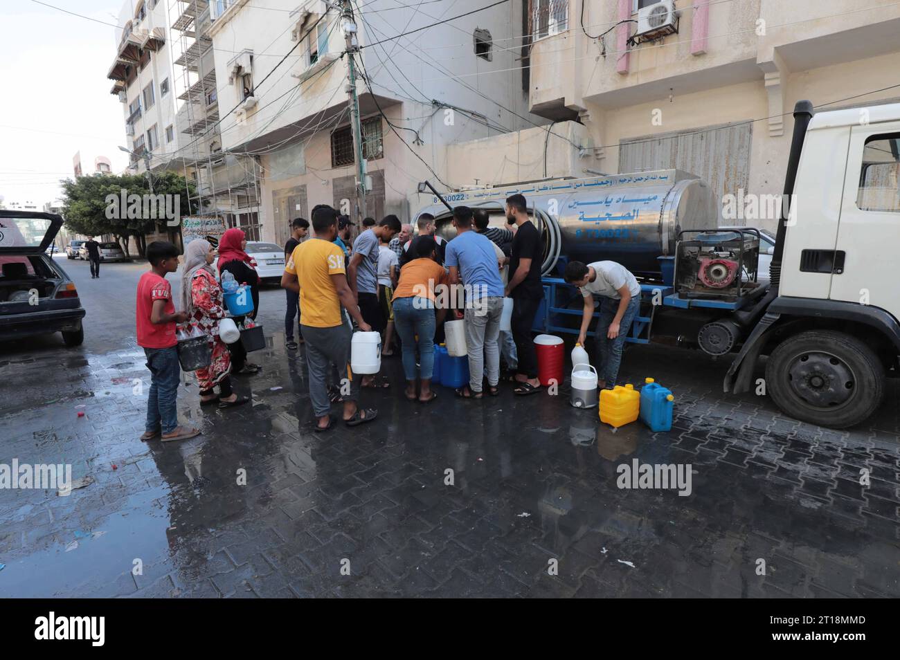 Palestinians fill their jerry cans with water from a public water ...