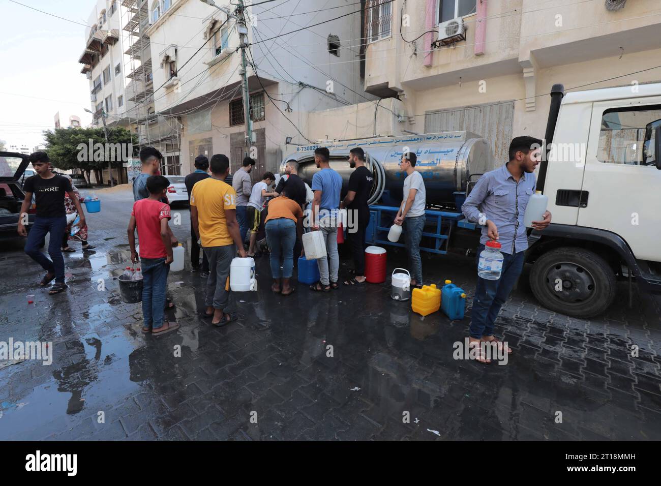 Palestinians fill their jerry cans with water from a public water ...