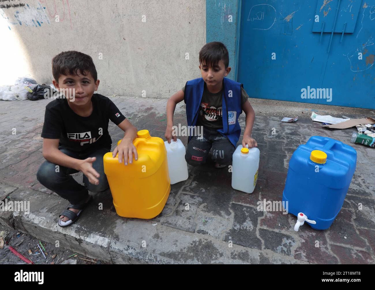 Palestinians fill their jerry cans with water from a public water ...