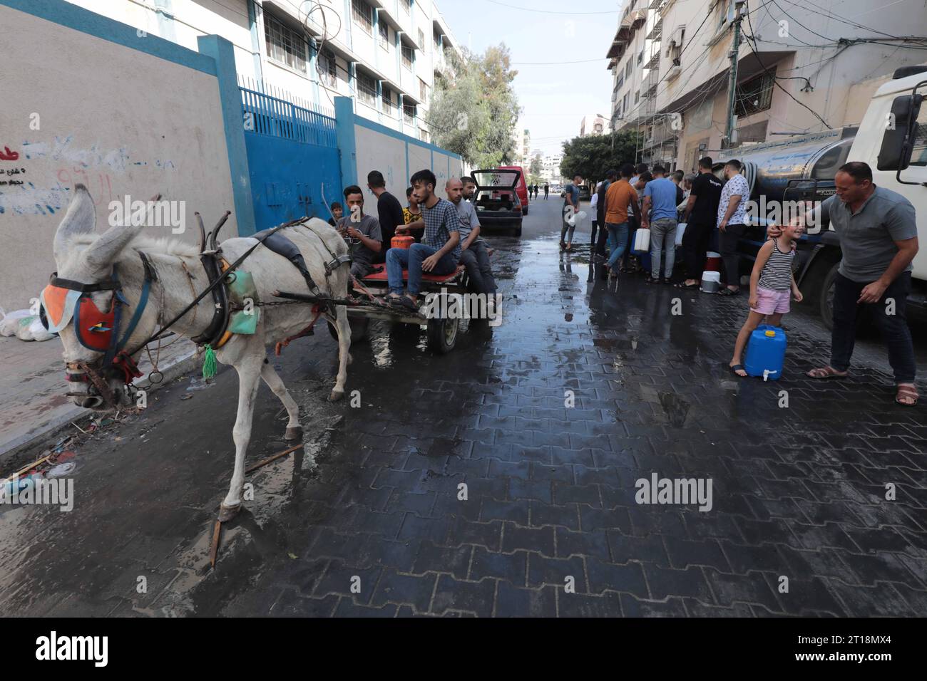 Palestinians fill their jerry cans with water from a public water ...