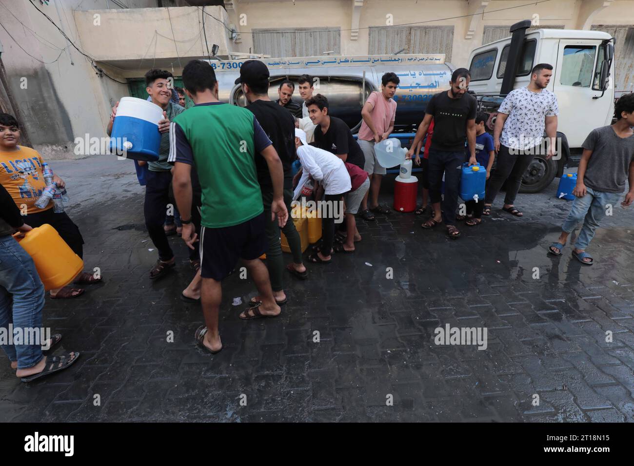 Palestinians fill their jerry cans with water from a public water ...