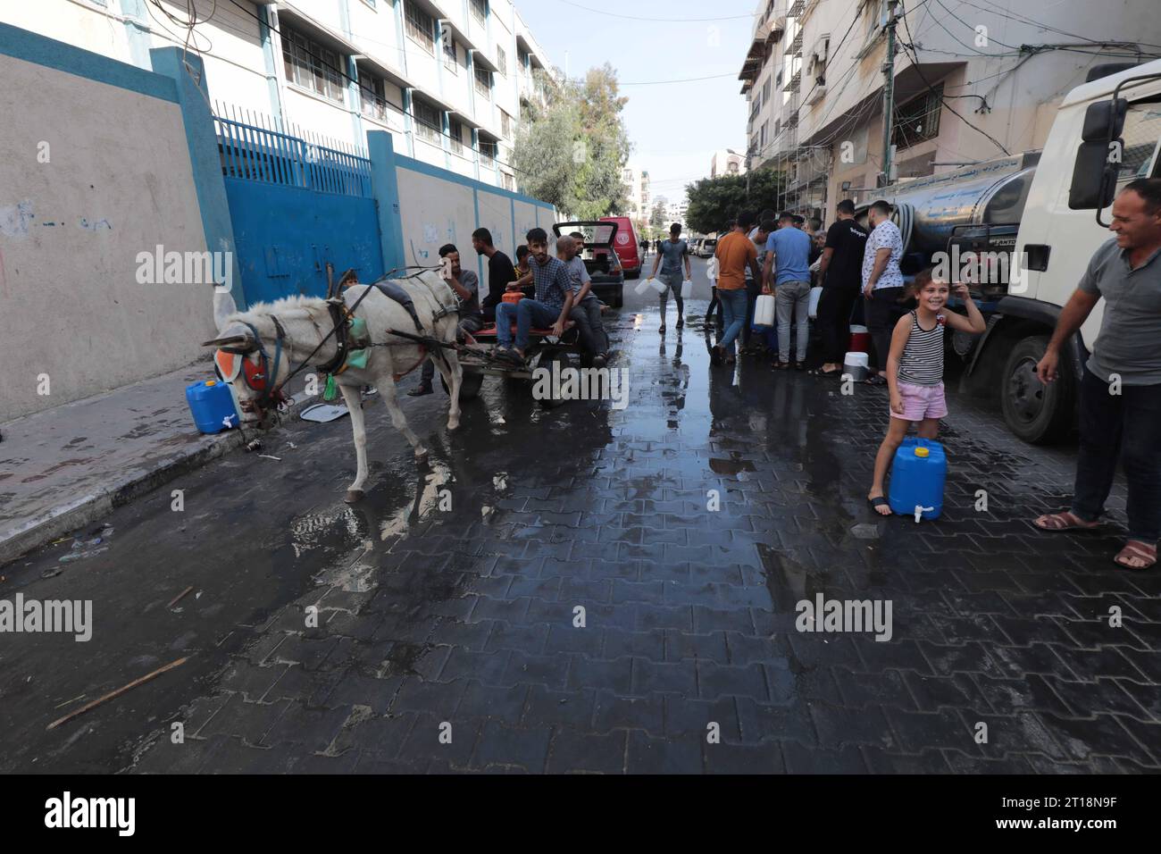 Palestinians fill their jerry cans with water from a public water ...