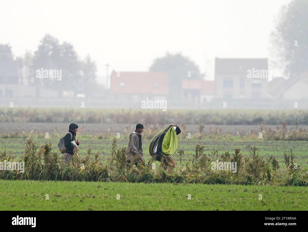People thought to be migrants carry their belongings as they are ...