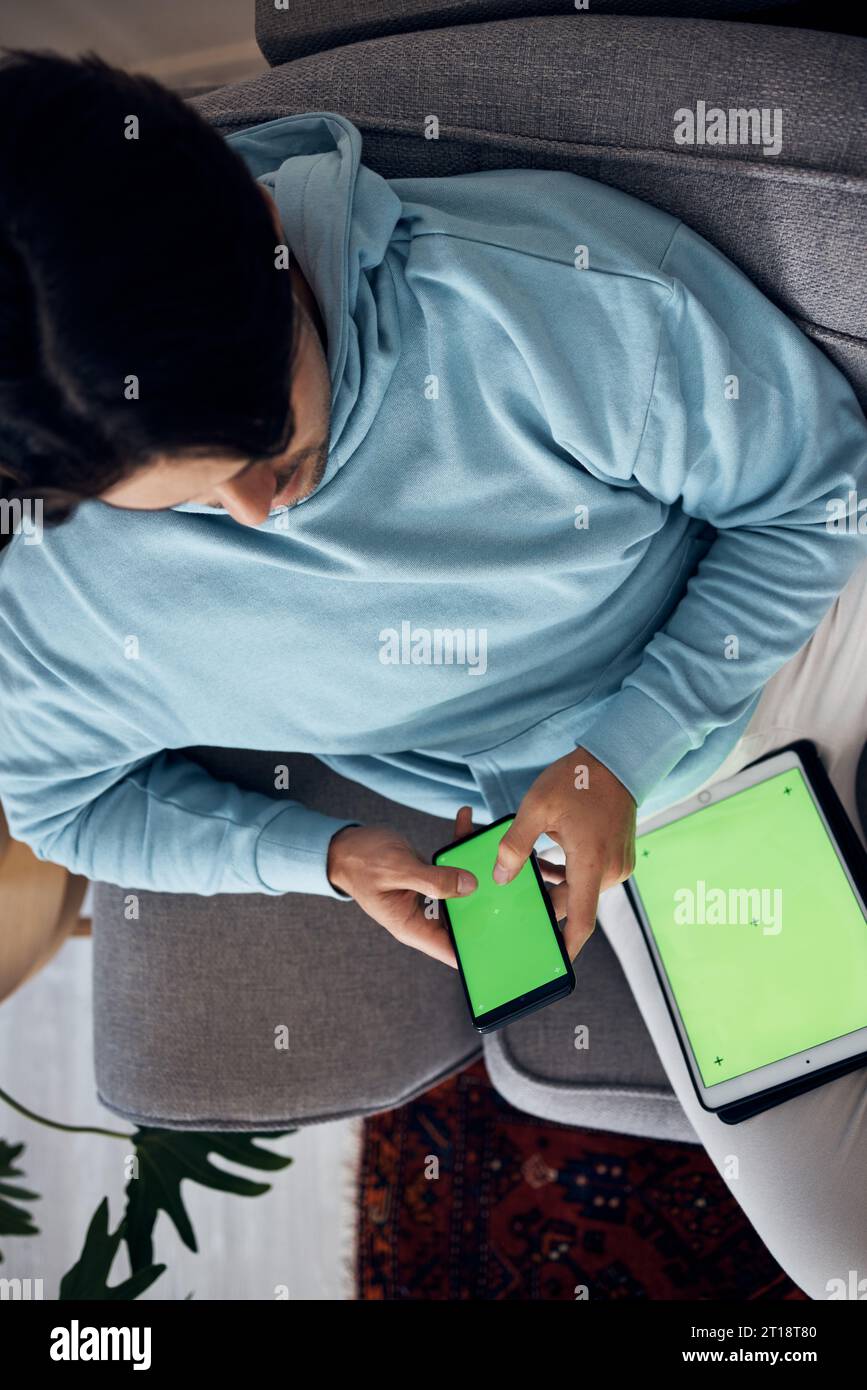 Phone, green screen and a man playing games on a sofa in the living ...