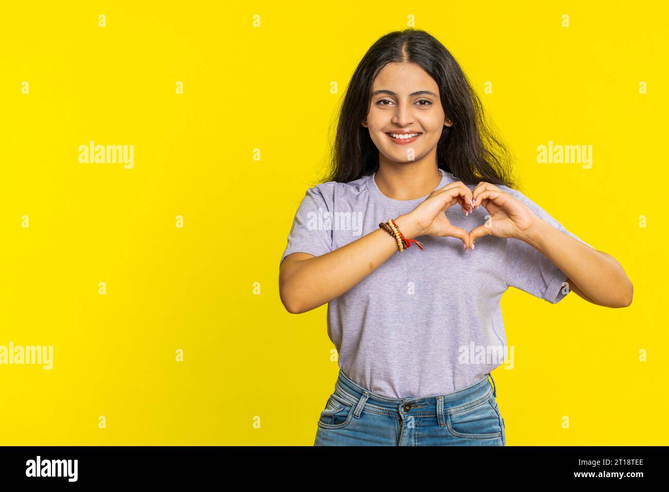 Woman in love. Smiling attractive Indian woman makes heart gesture ...