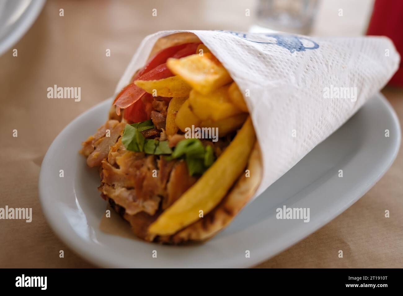 View of a delicious Greek pita gyro filled with French fries, tomato ...