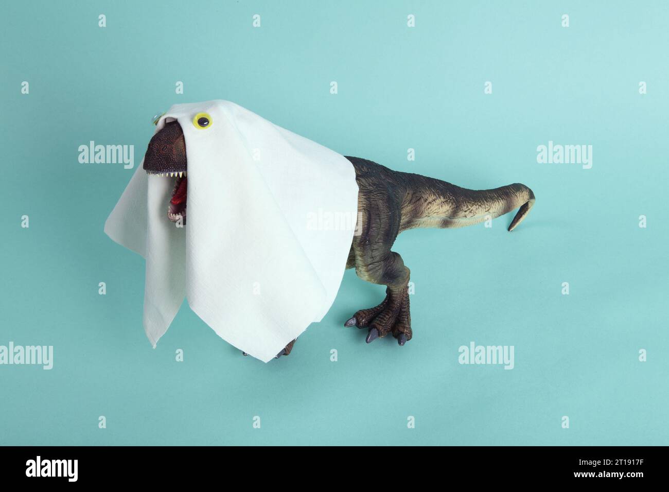 a plastic t-rex dinosaur figurine disguised as a ghost with a sheet and ...