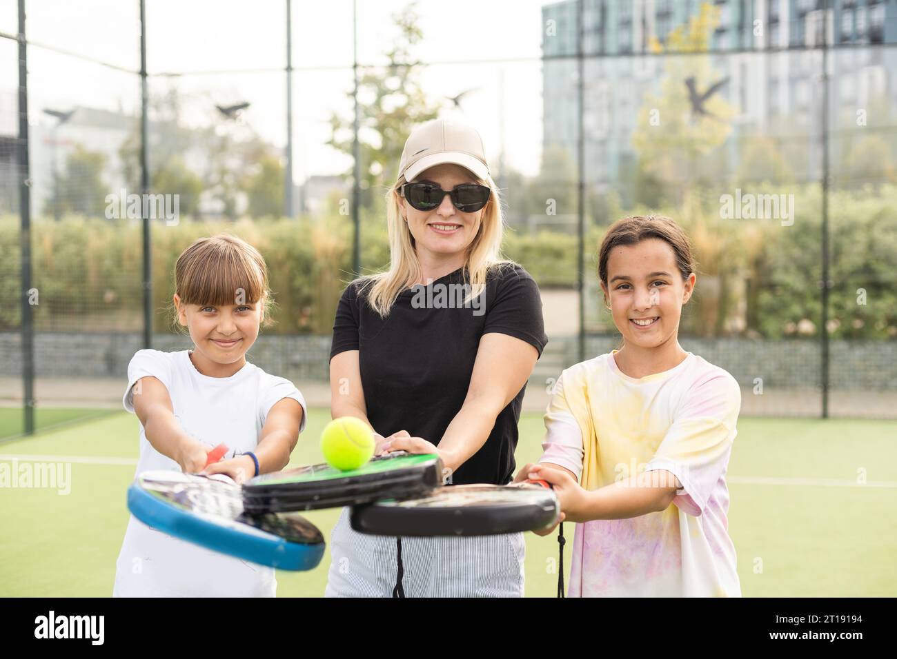 Young sporty woman with children playing padel game in court on sunny ...