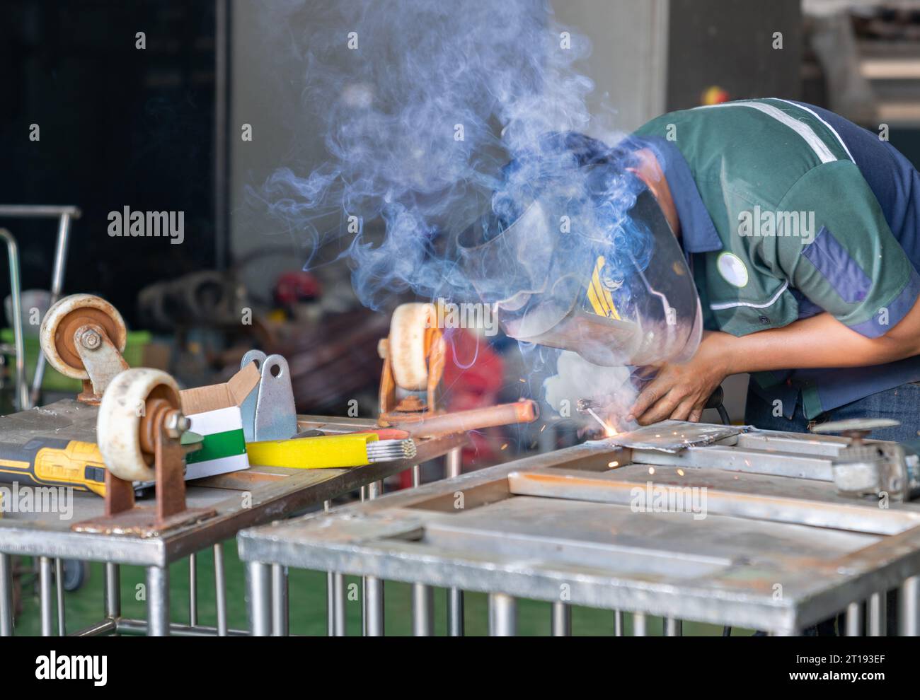 Technician welding wheel base stainless cart, spark and fume in ...