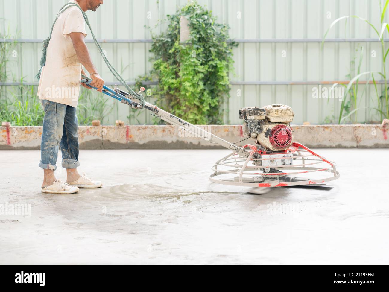Worker scrub a new concrete floor withe scrub machine in construction ...