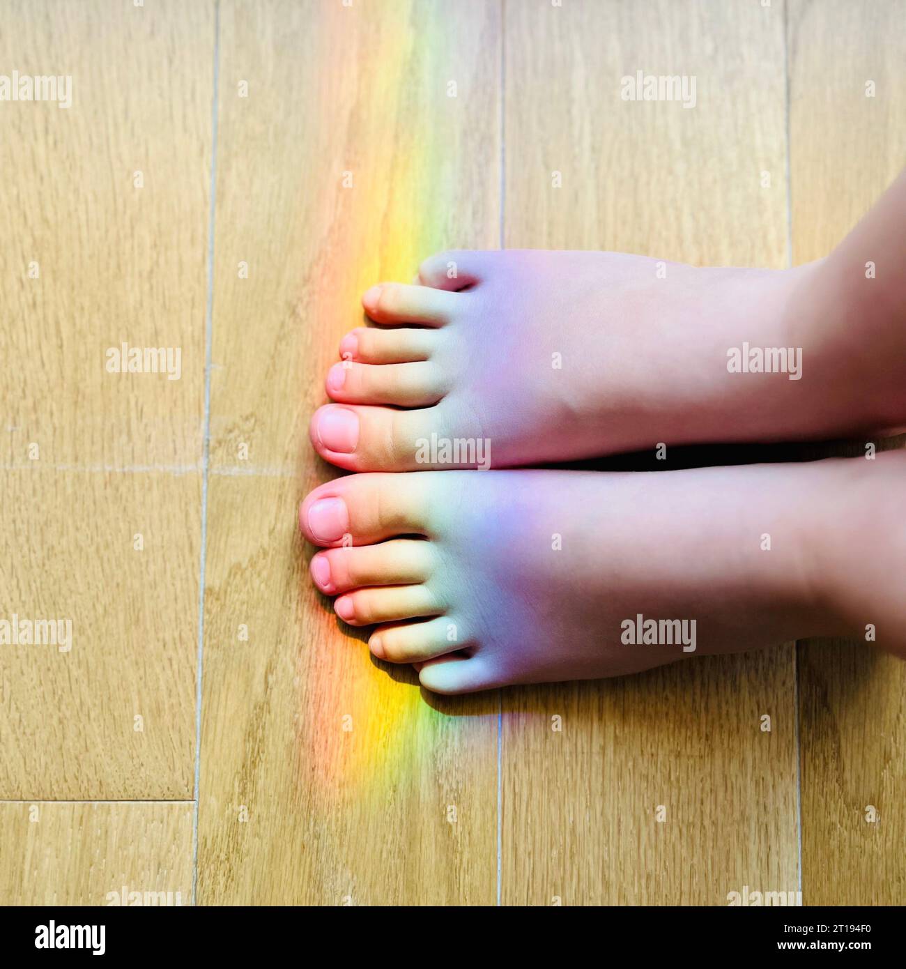 Overhead view of a rainbow of light across a child's feet Stock Photo ...