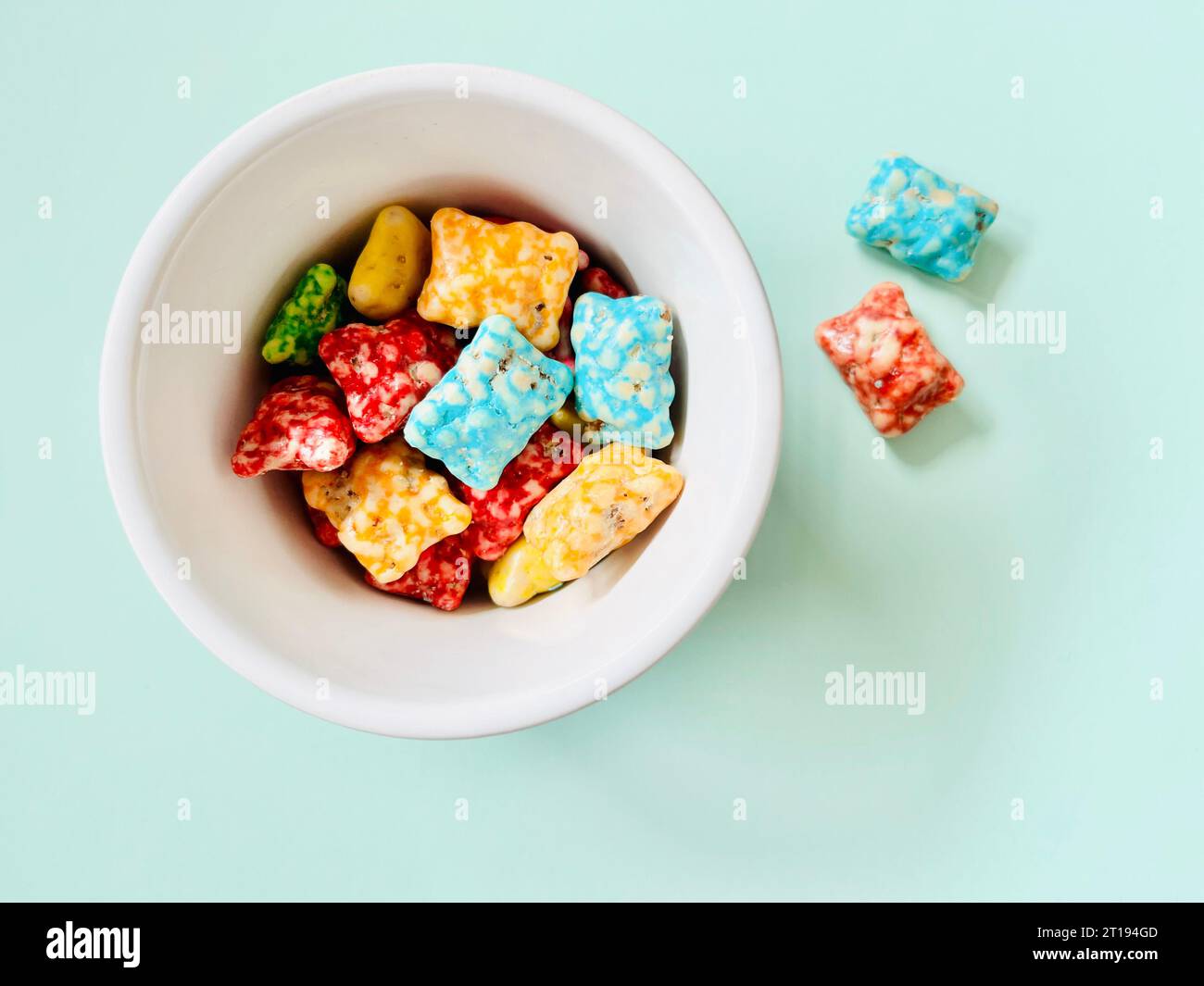 Overhead view of a bowl of multi coloured sweets on a turquoise ...