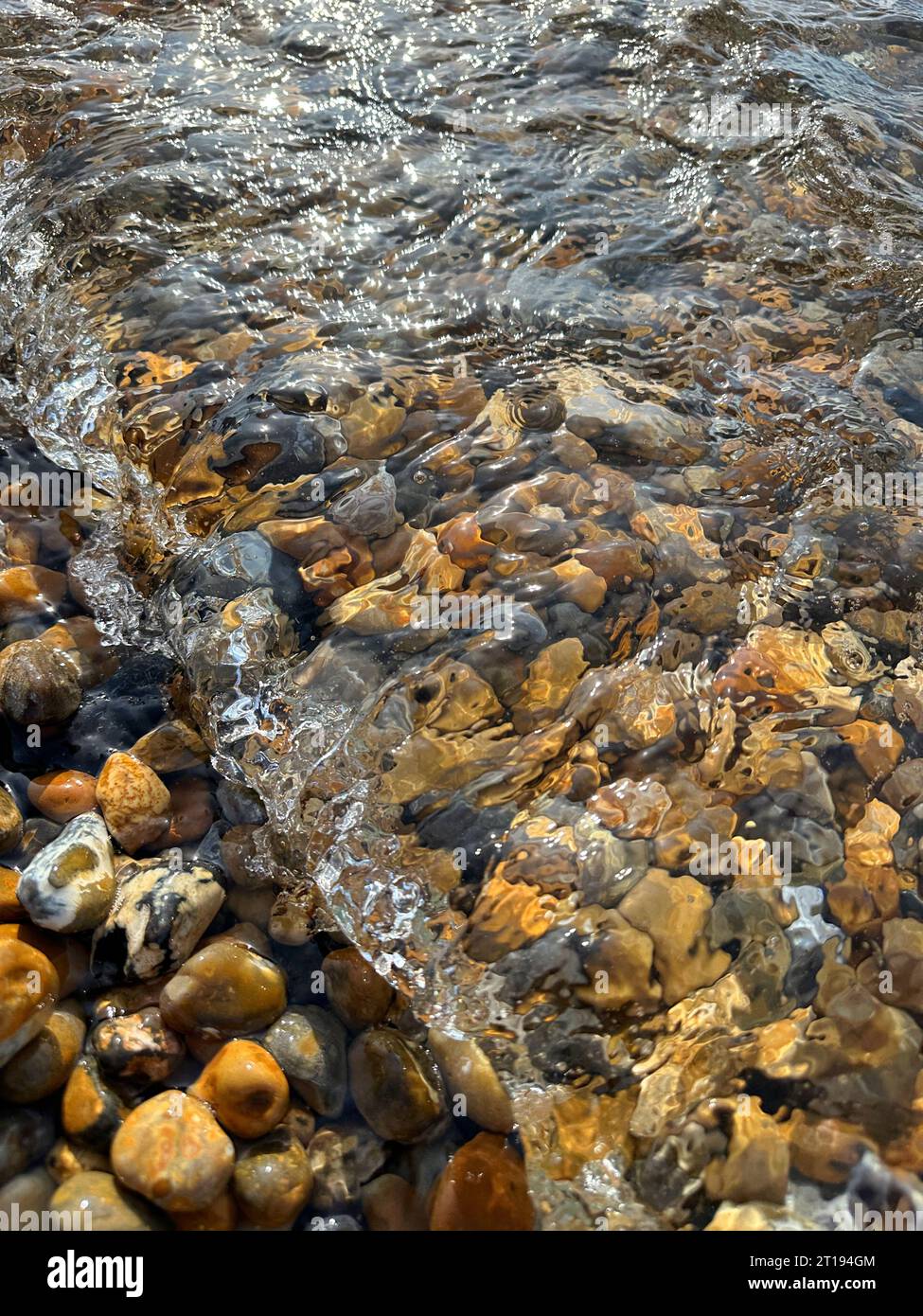 Close-up of clear water lapping over pebbles in the sea, Folkestone ...
