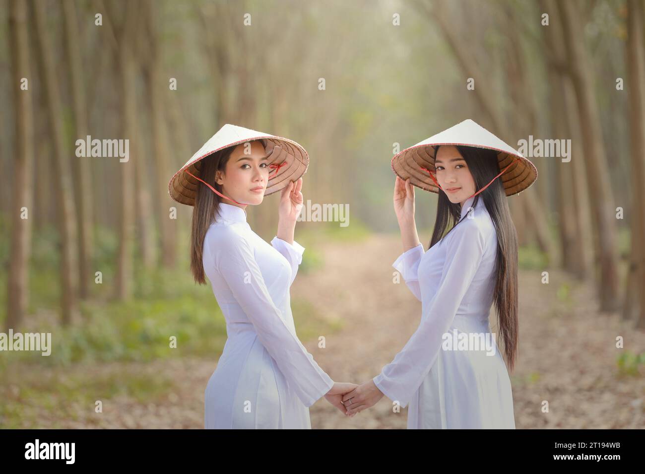 Two smiling women in traditional Vietnamese tunic dresses (ao dai) and ...