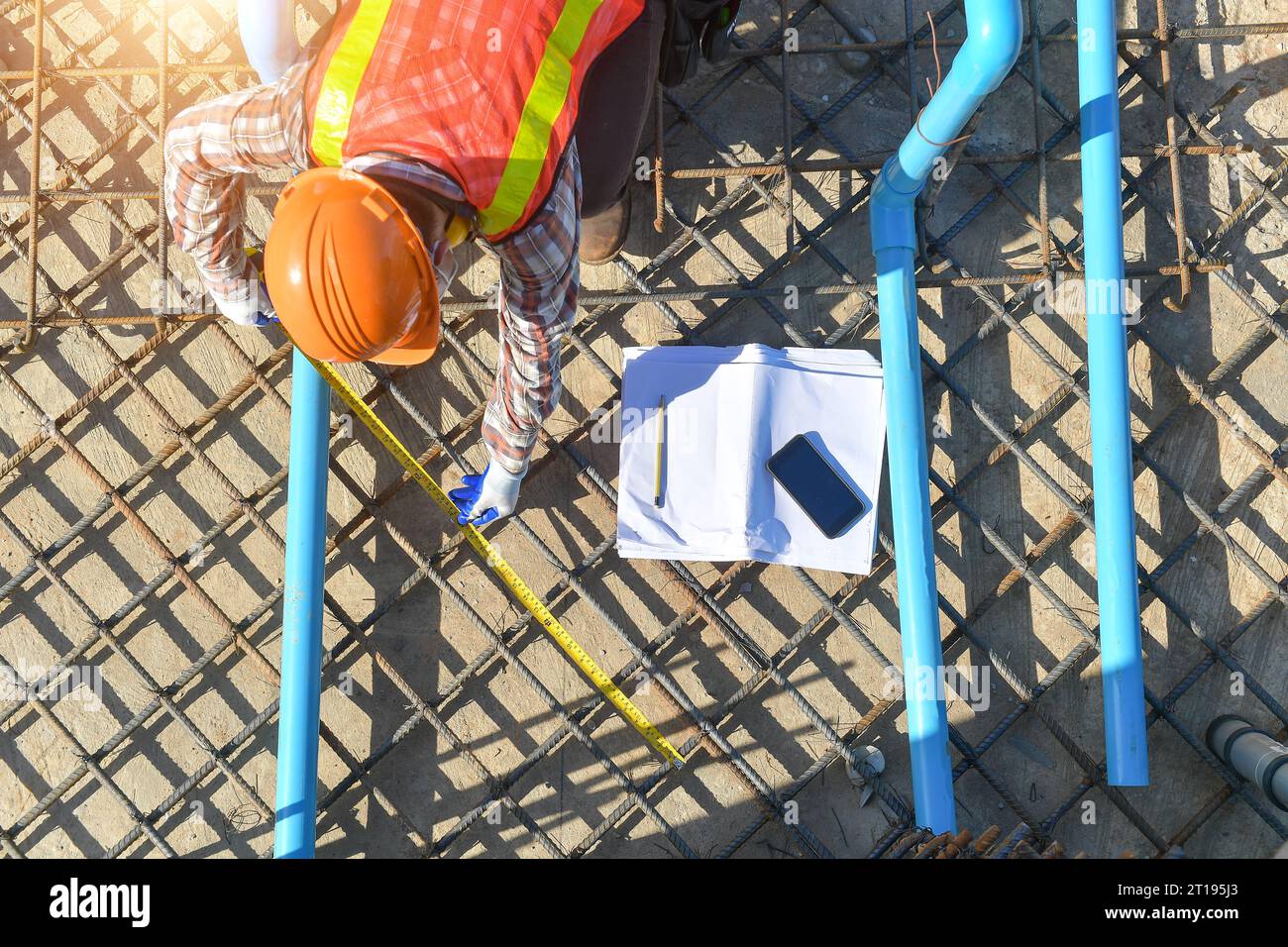 Overhead view of a construction worker measuring metal foundations on a ...