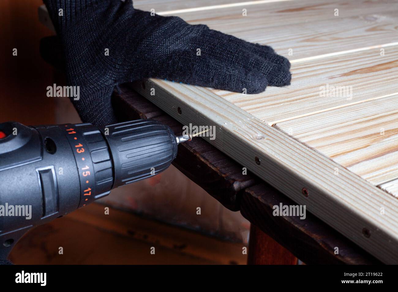 Carpentry work. The self-tapping screw is screwed into a wooden beam ...