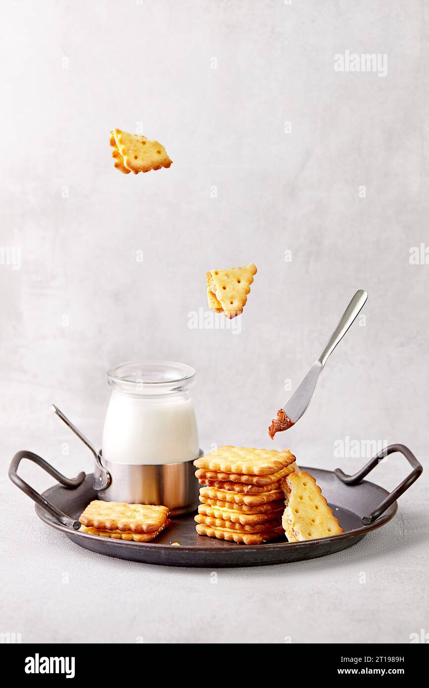 Stack of crackers and milk on a metal tray with a caramel covered knife ...