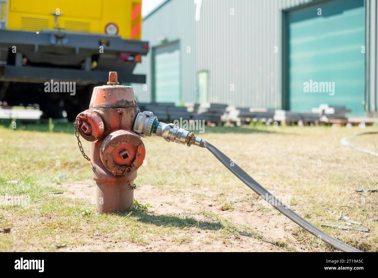 An aged red fire hydrant with an attached hose stands as an iconic ...