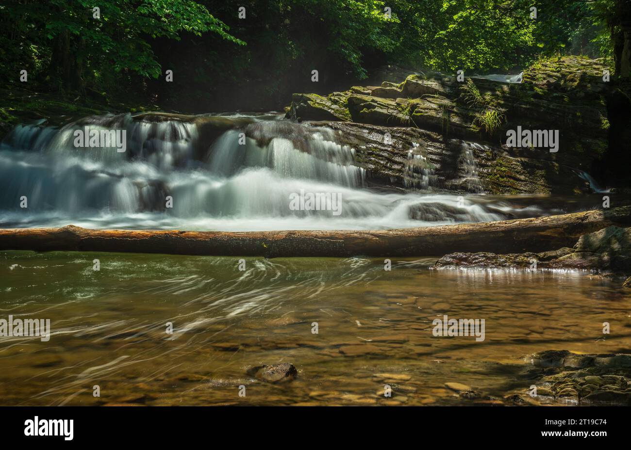 a very charming waterfall in the mountains, blurry water flows in a ...