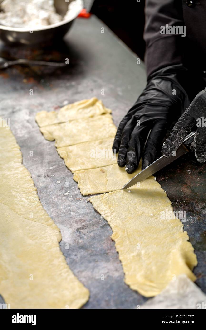 Process of cutting dough for bagels. The confectioner cuts the puff ...
