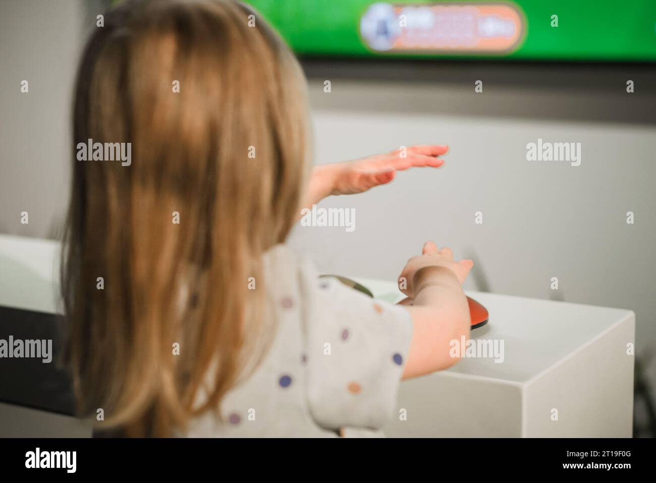 Toddler girl looking at a big television screen with interactive ...