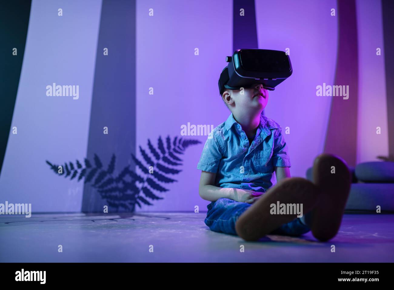 Little boy wearing VR headset sitting on the floor in the museum ...
