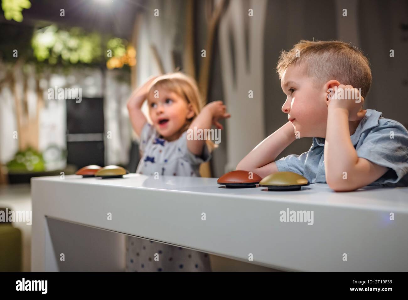 Two young children, a toddler girl and a boy looking at a big ...