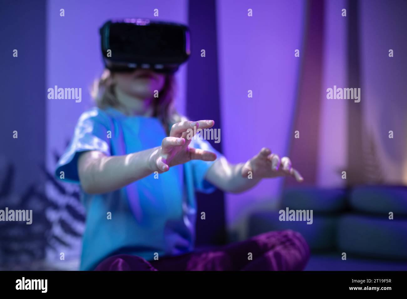 School aged girl child in VR glasses sitting on the floor, having an ...