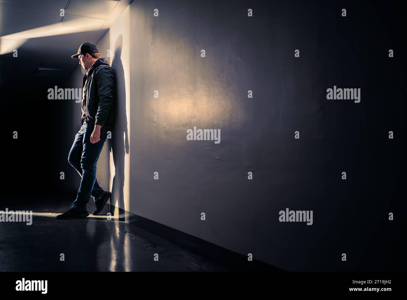 Serious sad man standing in dark corridor. Mystery guy in spotlight ...