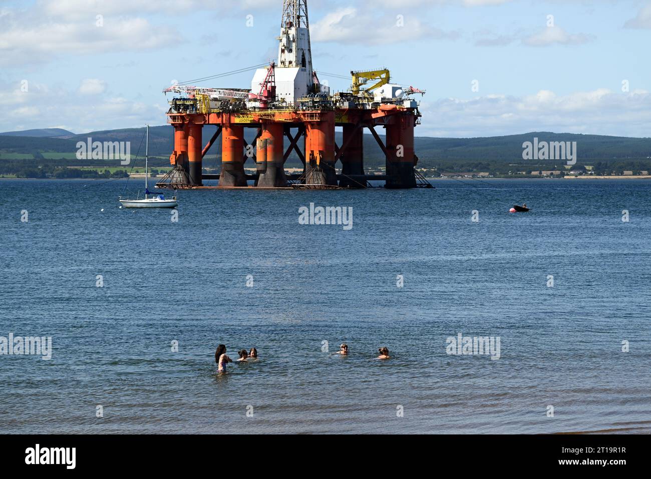 Five women swimming before an oil rig anchored in the Cromarty firth ...