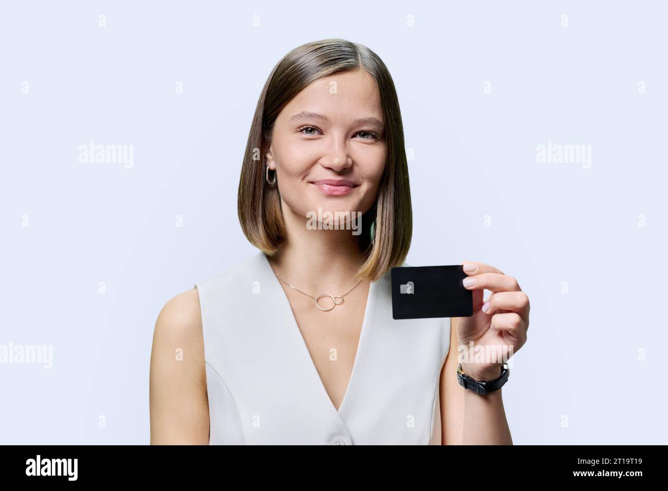 Young woman bank employee showing credit card, on white background ...