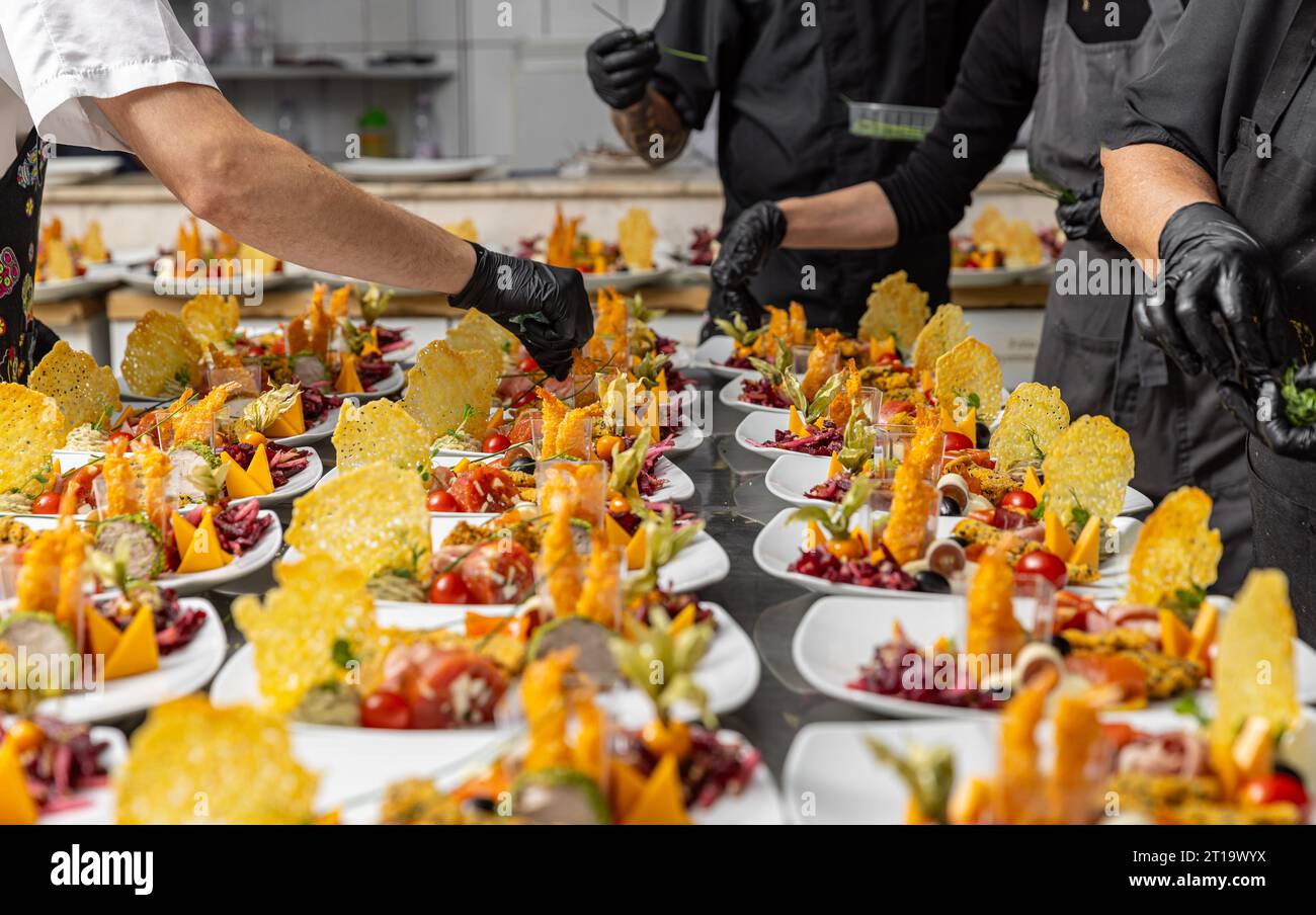 Cooks are garnishing appetizer plates in restaurant kitchen board Stock ...
