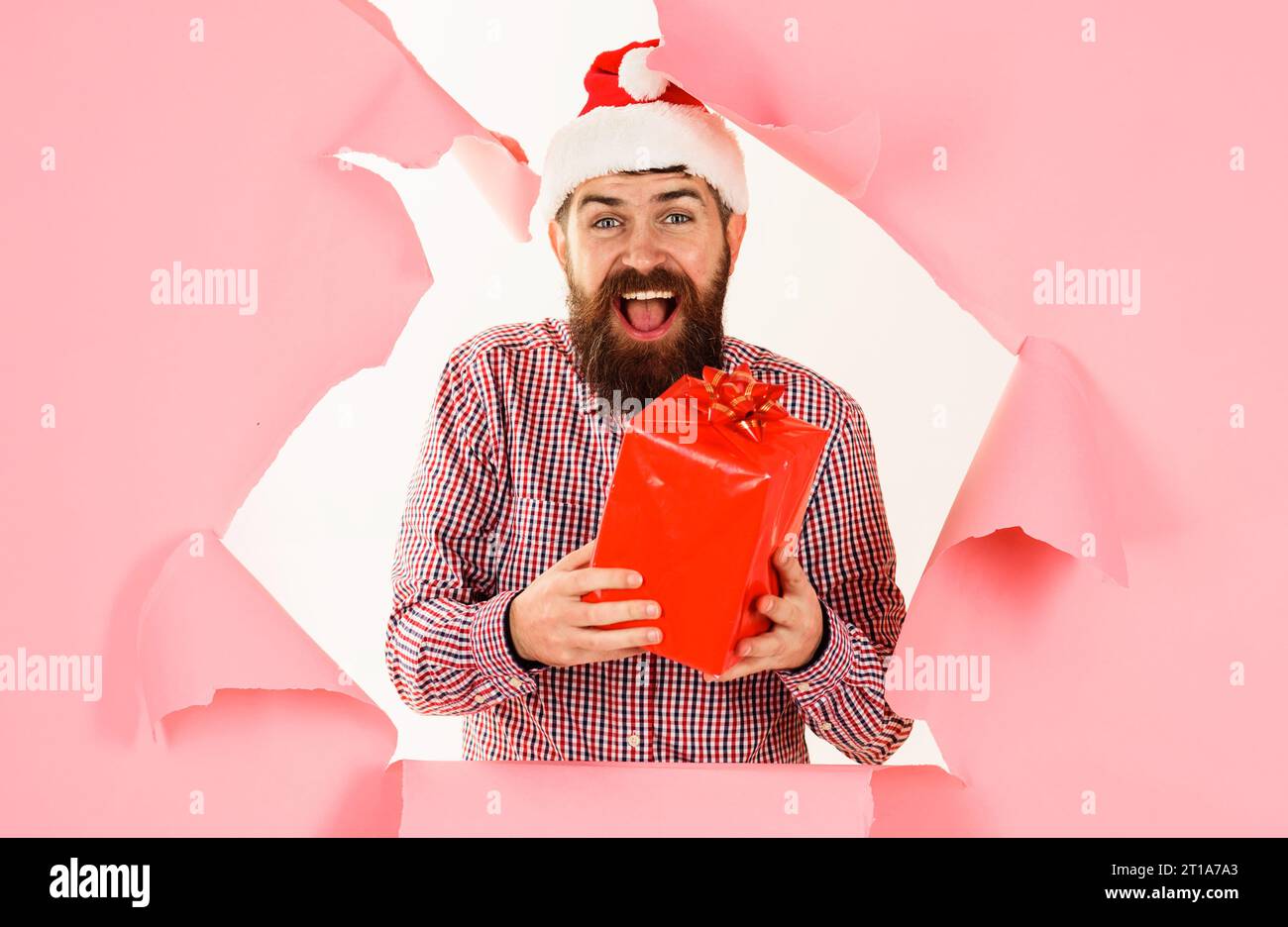 Happy bearded man in Santa hat with Christmas gift looking through ...