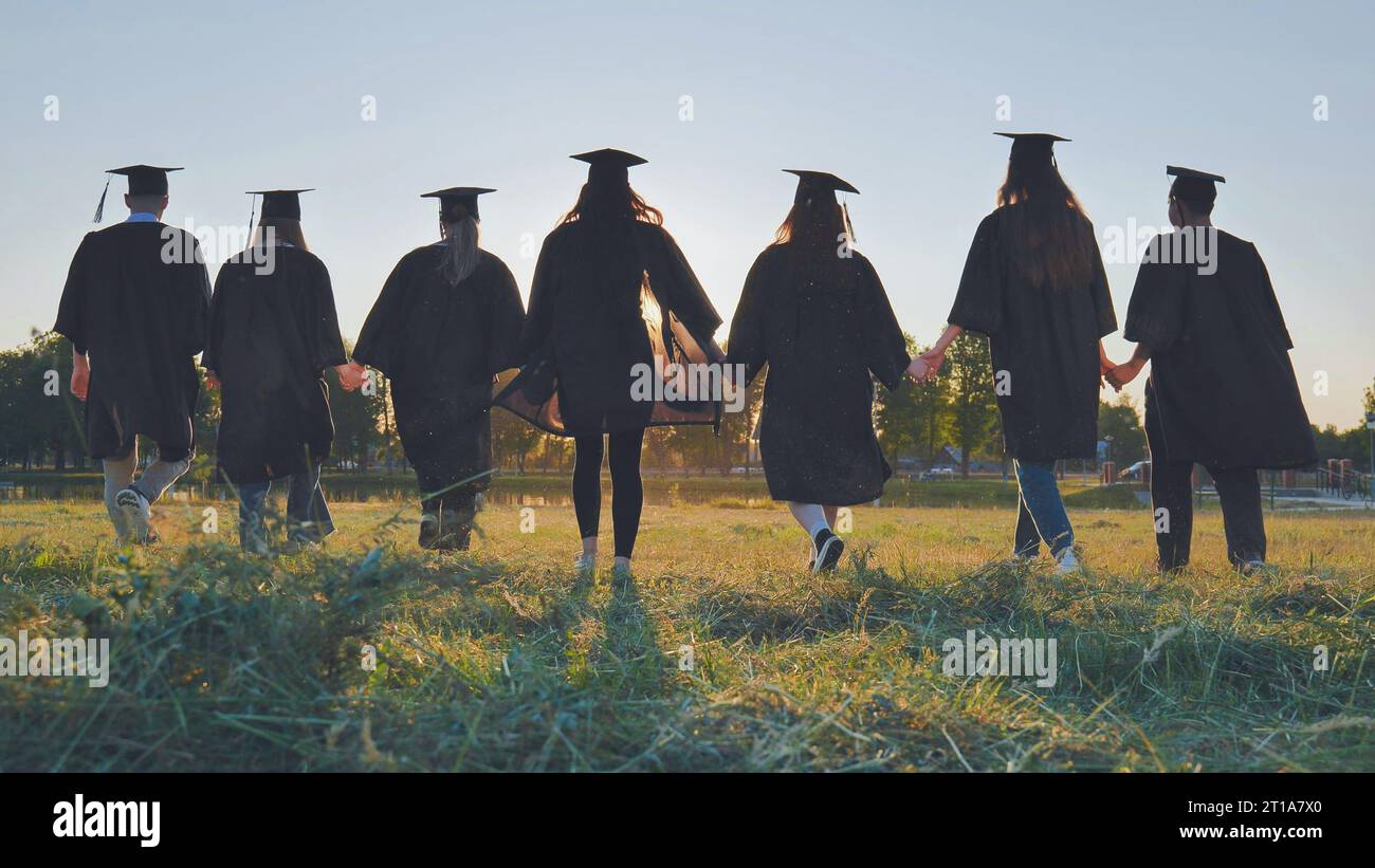 College graduates hold hands at sunset to meet the future and the sun ...