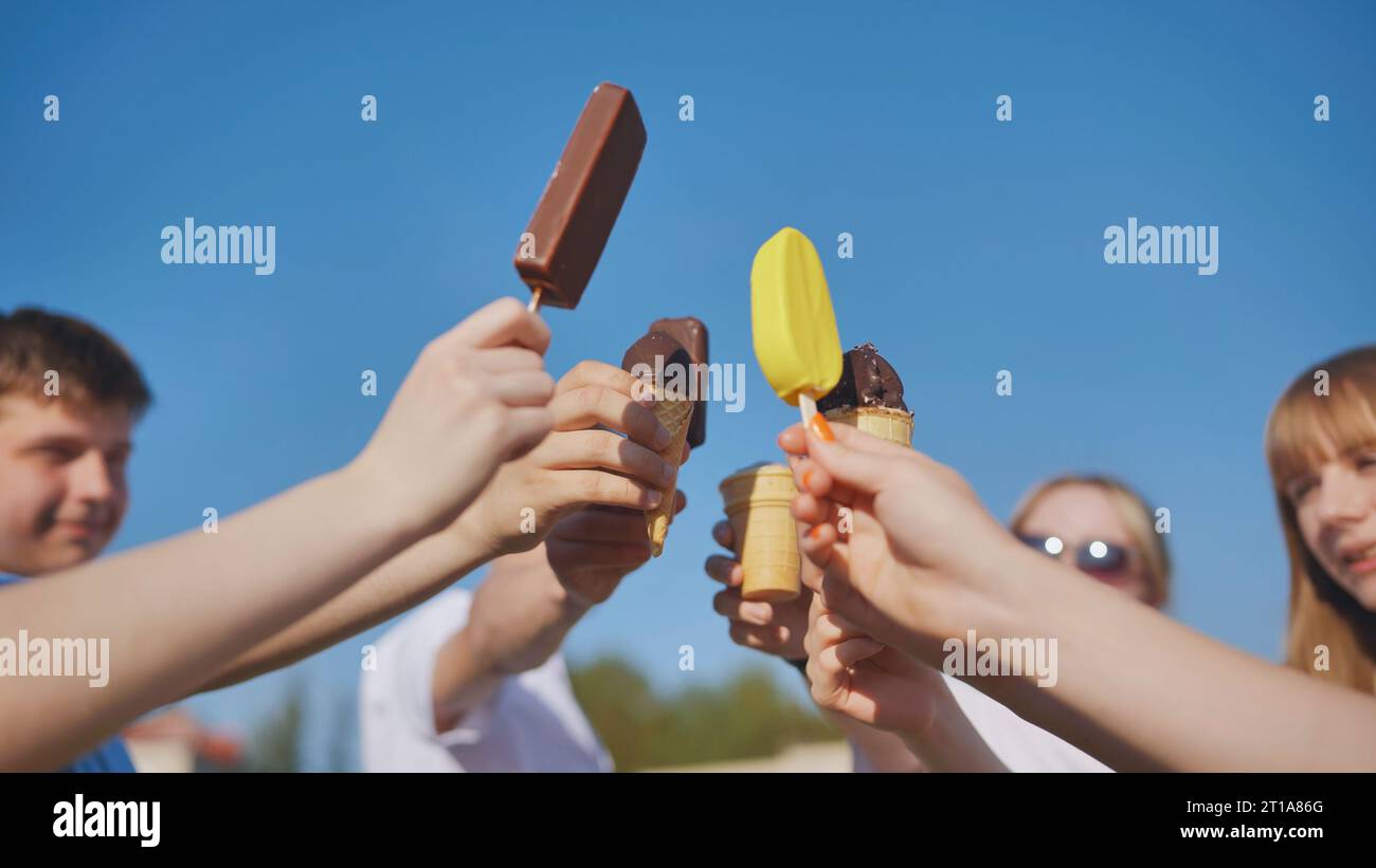 Friends link together colorful popsicles on a stick Stock Photo - Alamy