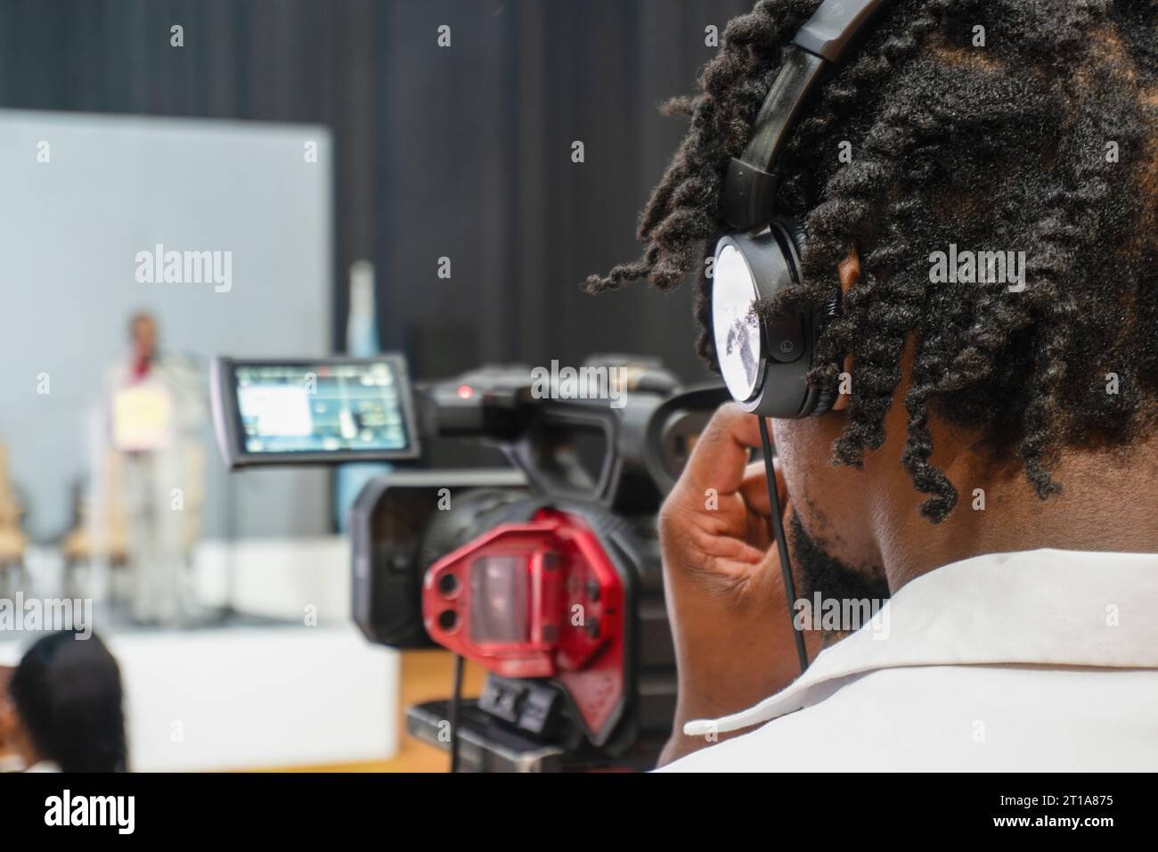 african cameraman with dreadlocks with camera filming an event indoors ...