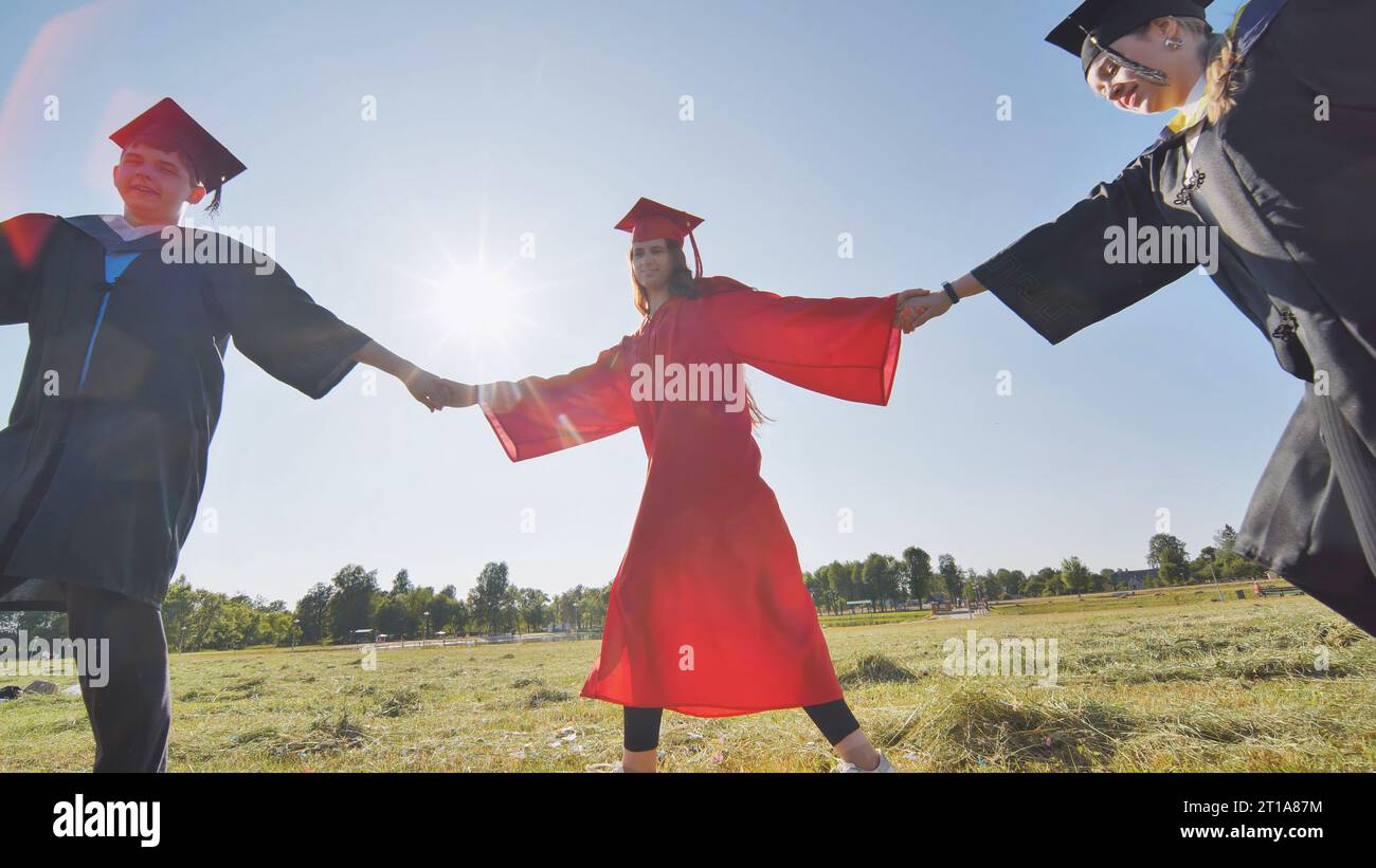 College graduates holding hands run in a round dance Stock Photo - Alamy