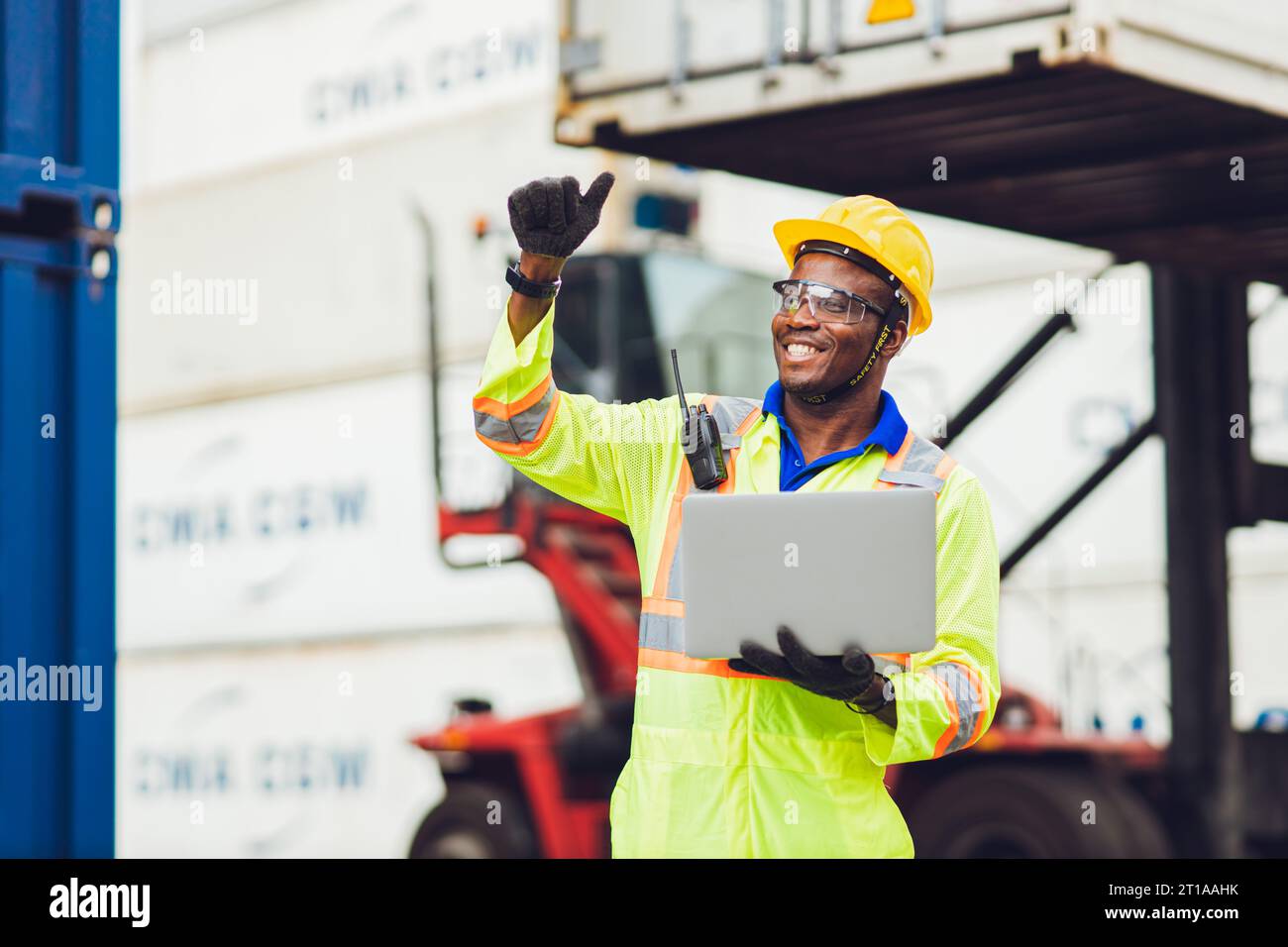 African male dock worker control loading containers cargo at warehouse container shipyard ...