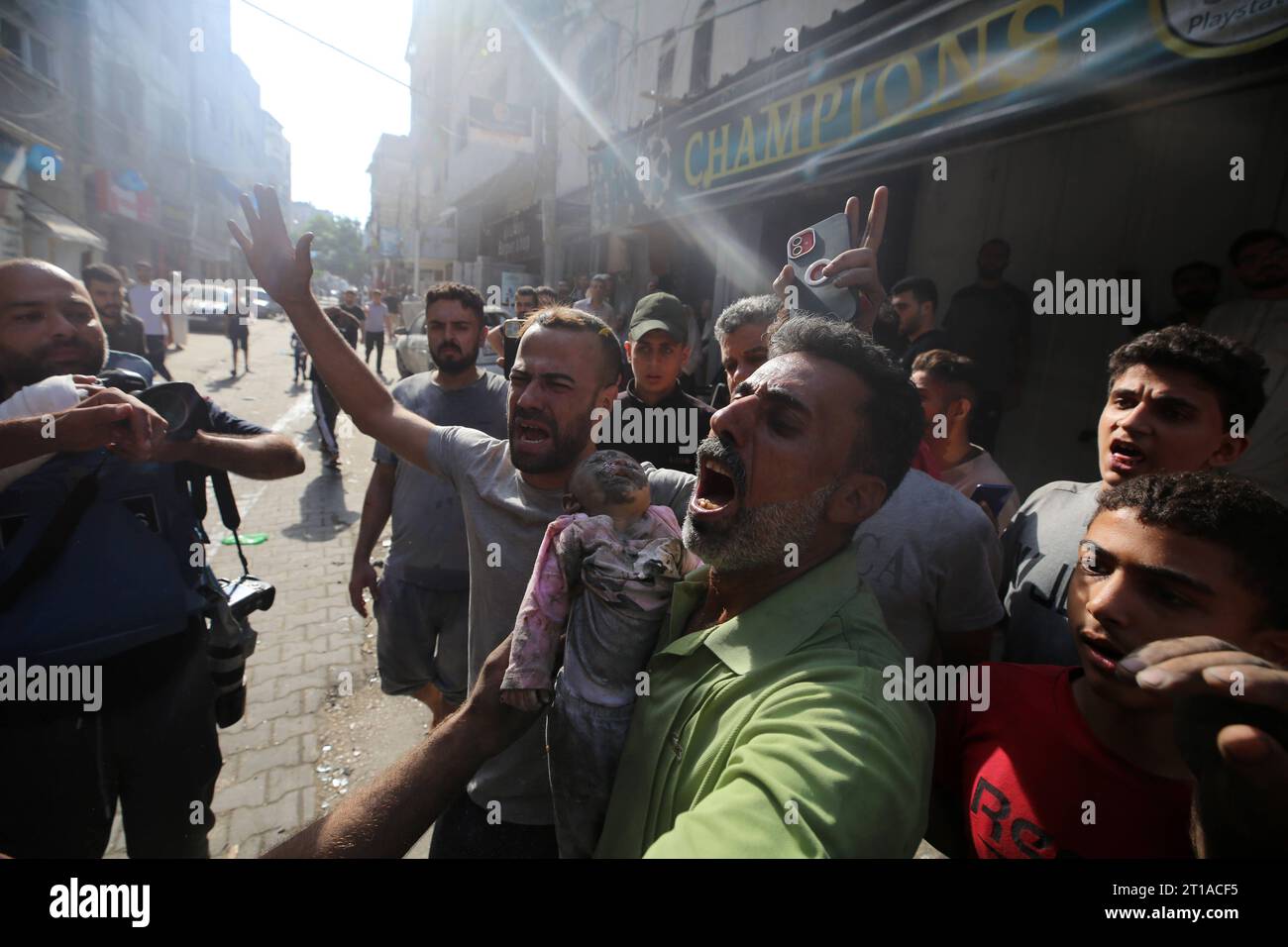 Palestinians holds the dead body of a baby killed in the attack on Al ...