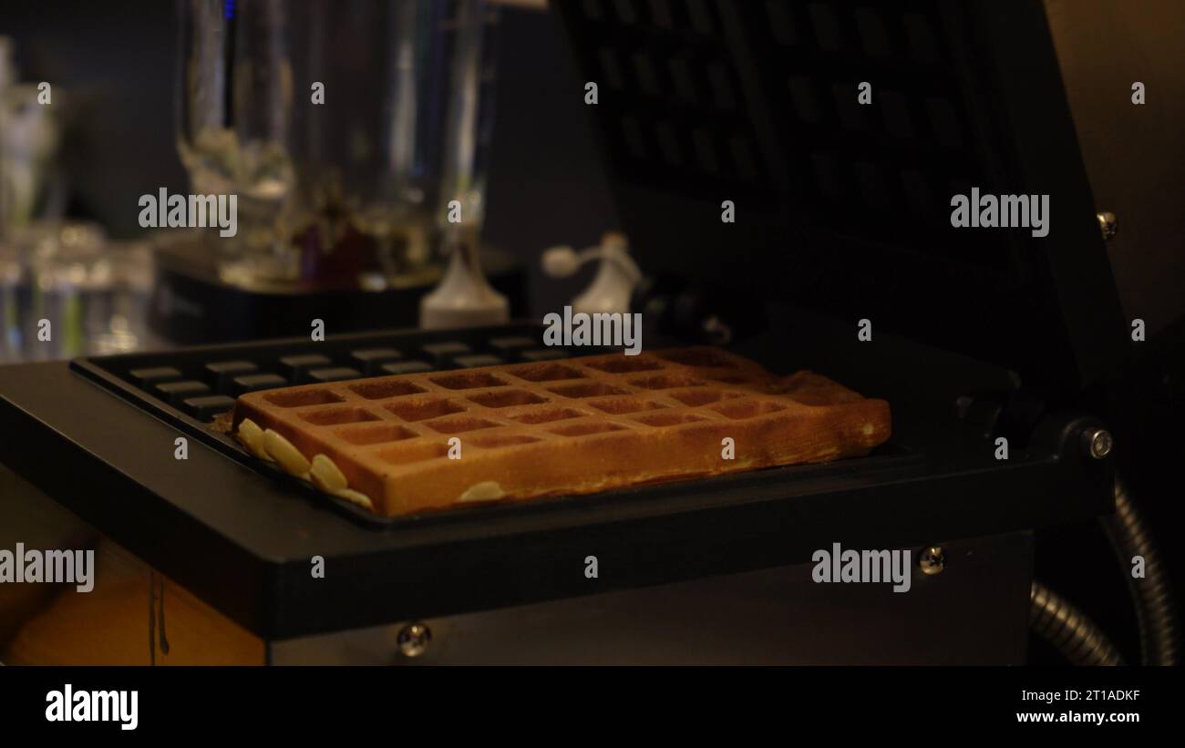 Cooking Belgian waffles in a waffle maker in a cafe. Close-up of a chef ...