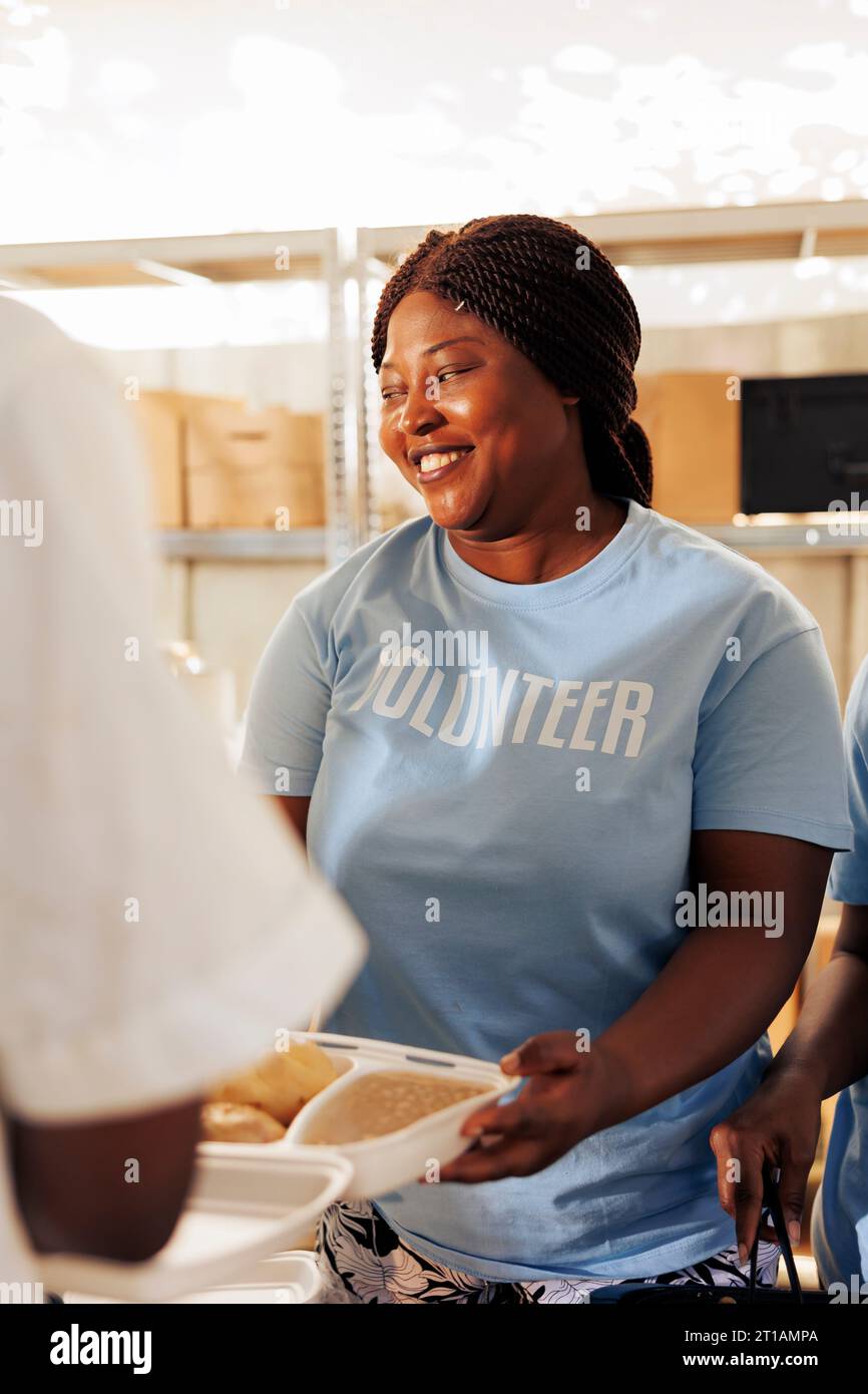 Friendly black woman giving free, hot meals to homeless people at a ...