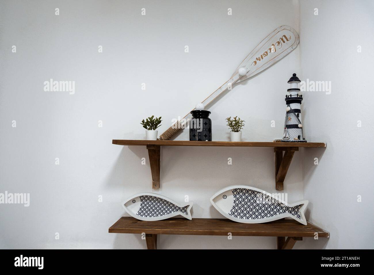 decorative fish, lighthouse and plants against white wall on wooden ...