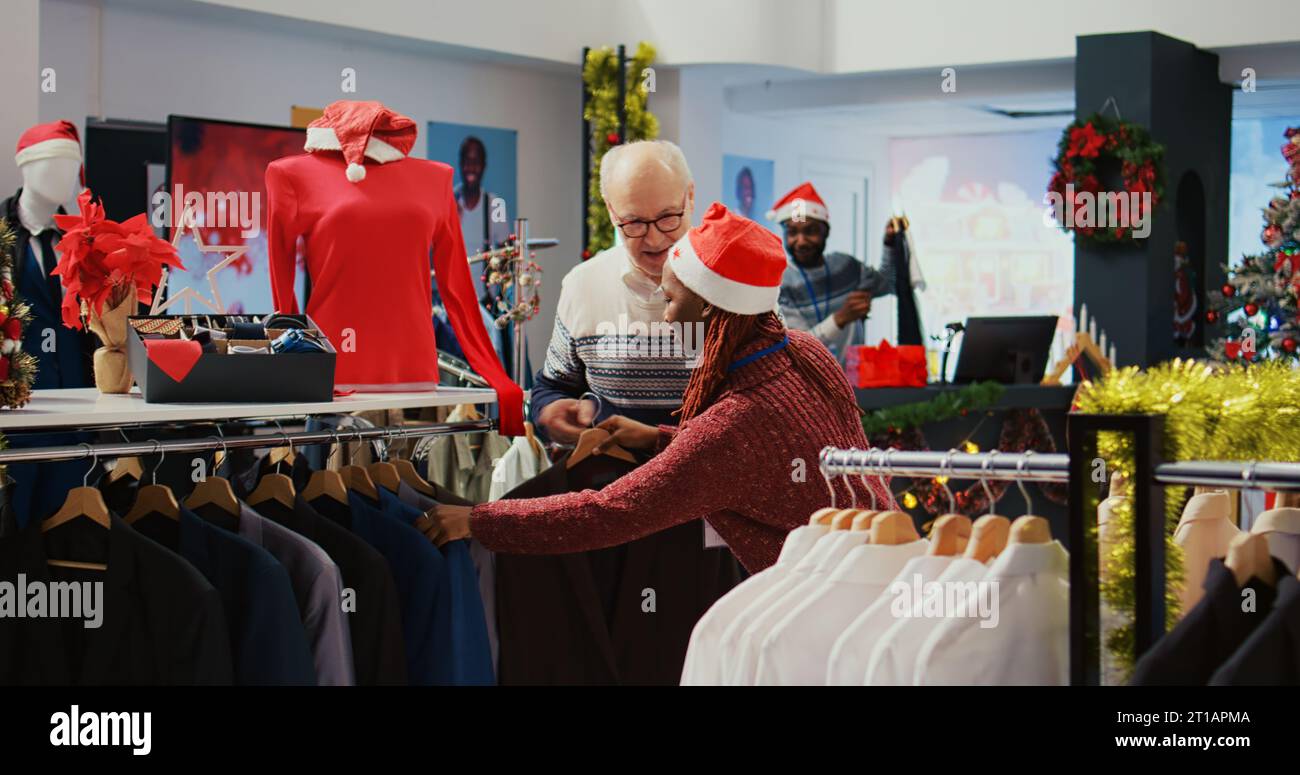 Elderly client being helped by retail assistant in festive decorated ...